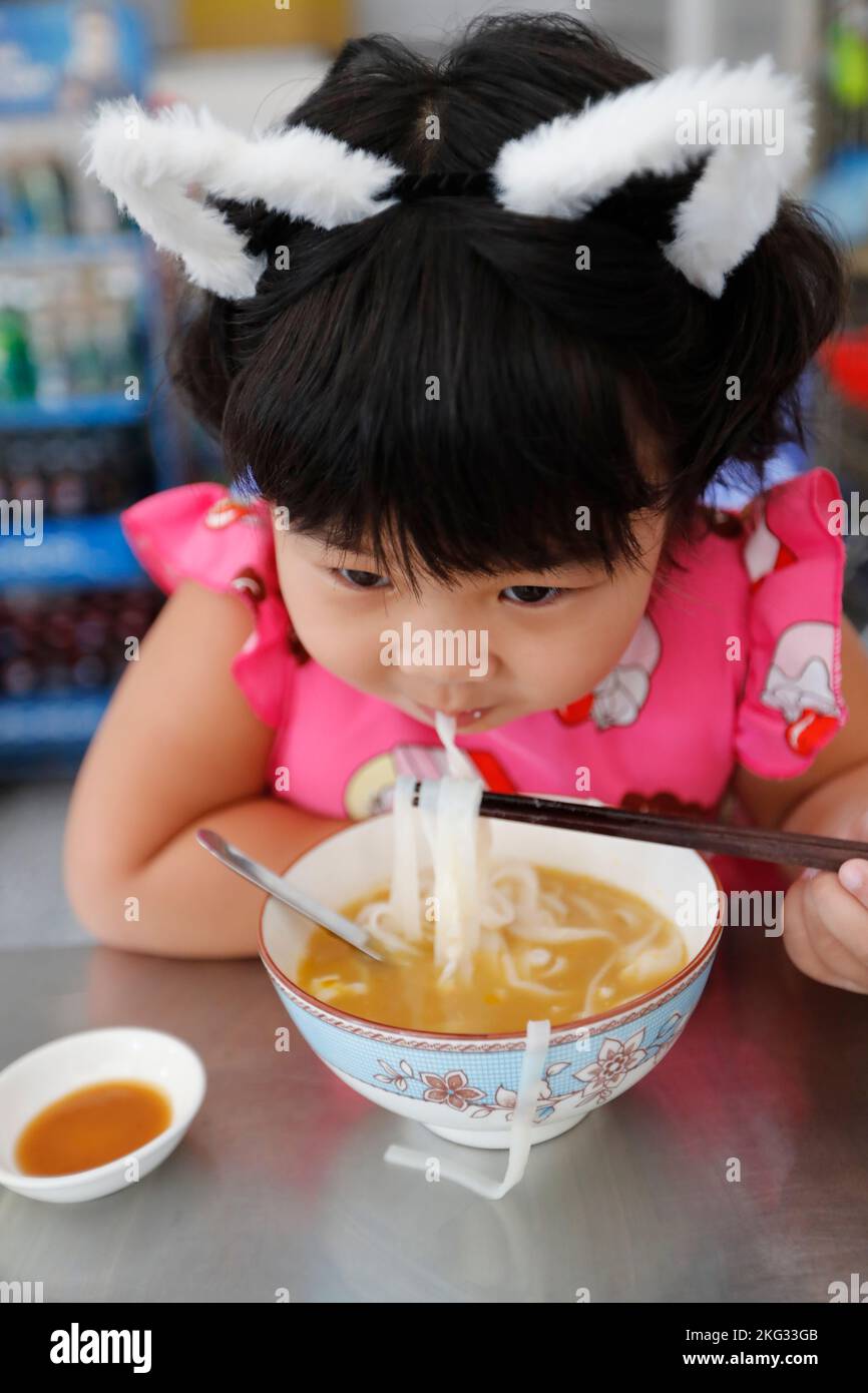 Girl eat traditional Vietnam Pho Bo beef noodle soup in restaurant. Tan ...