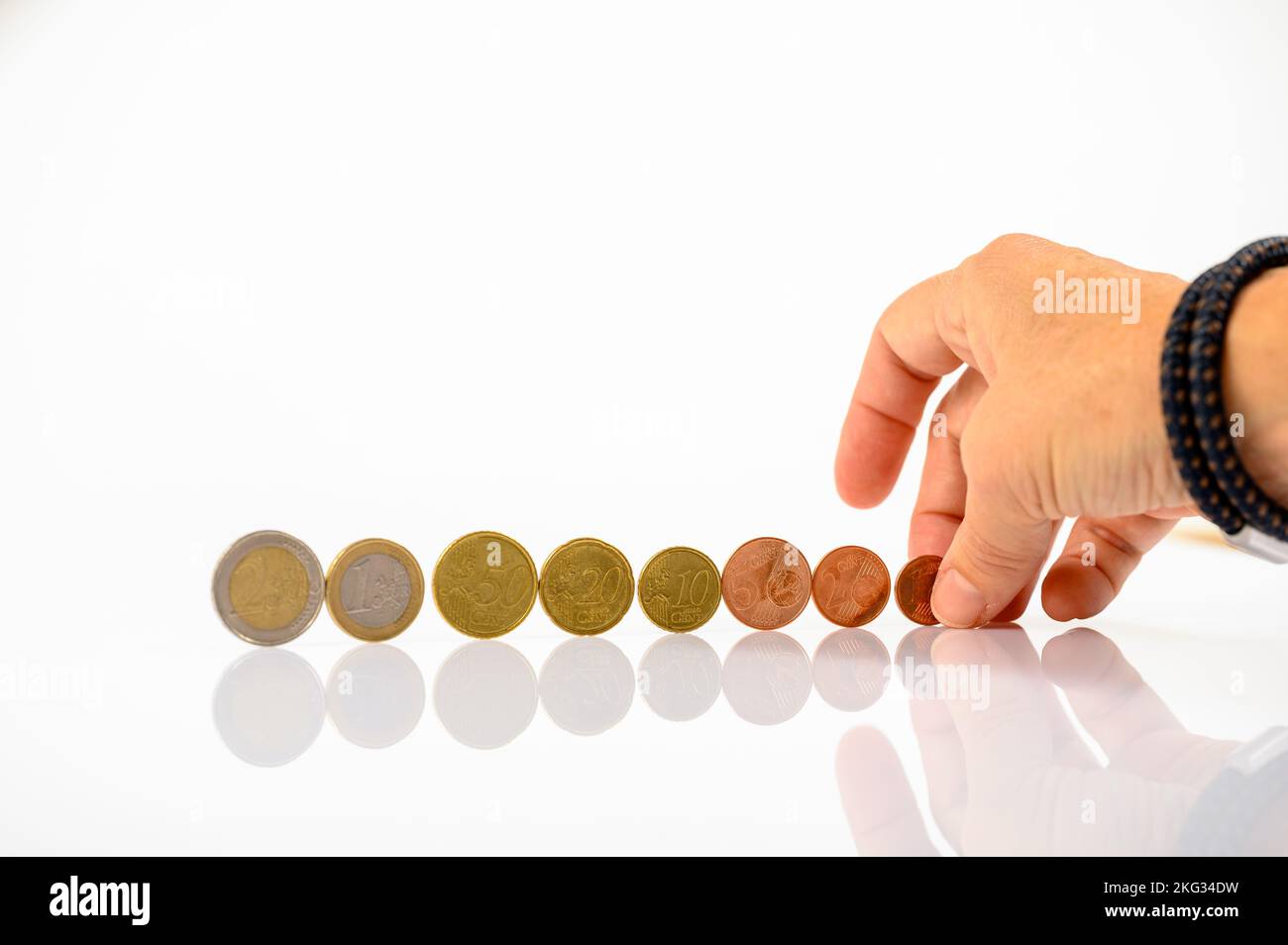 woman hand places complete set of euro coins upright on a white table ...
