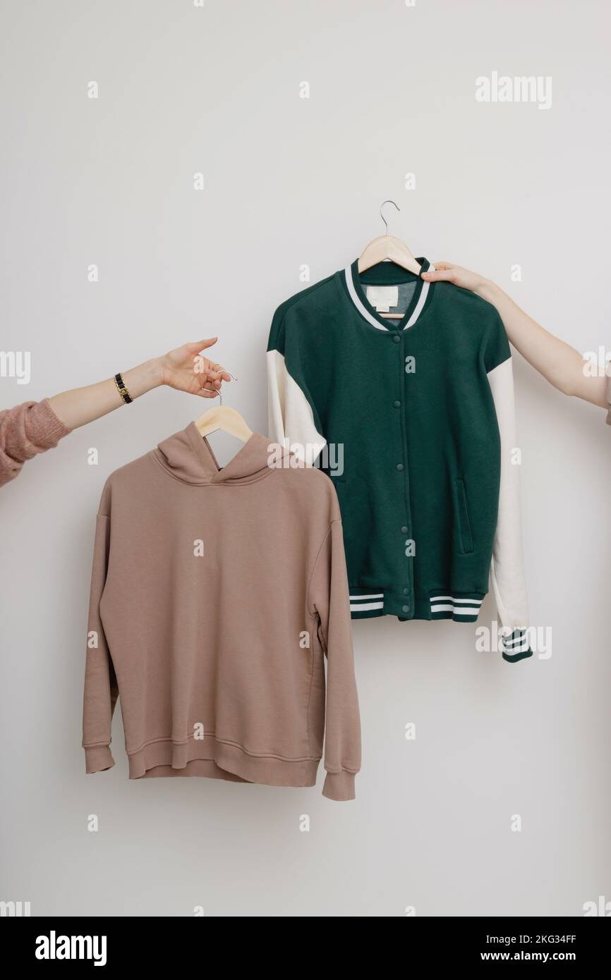 Two hands holding clothes on hangers. Basic wardrobe concept Stock ...
