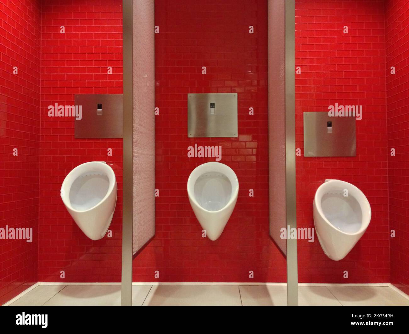The urinals on the red tiled wall of the bathroom Stock Photo - Alamy