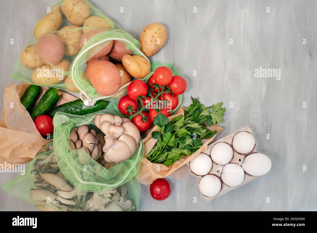 Vegetables in reusable net bags on grey wooden background, top view ...