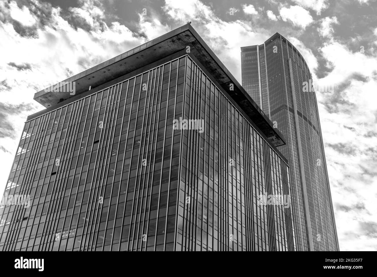A grayscale shot of the Montparnasse tower against a cloudy blue sky in ...