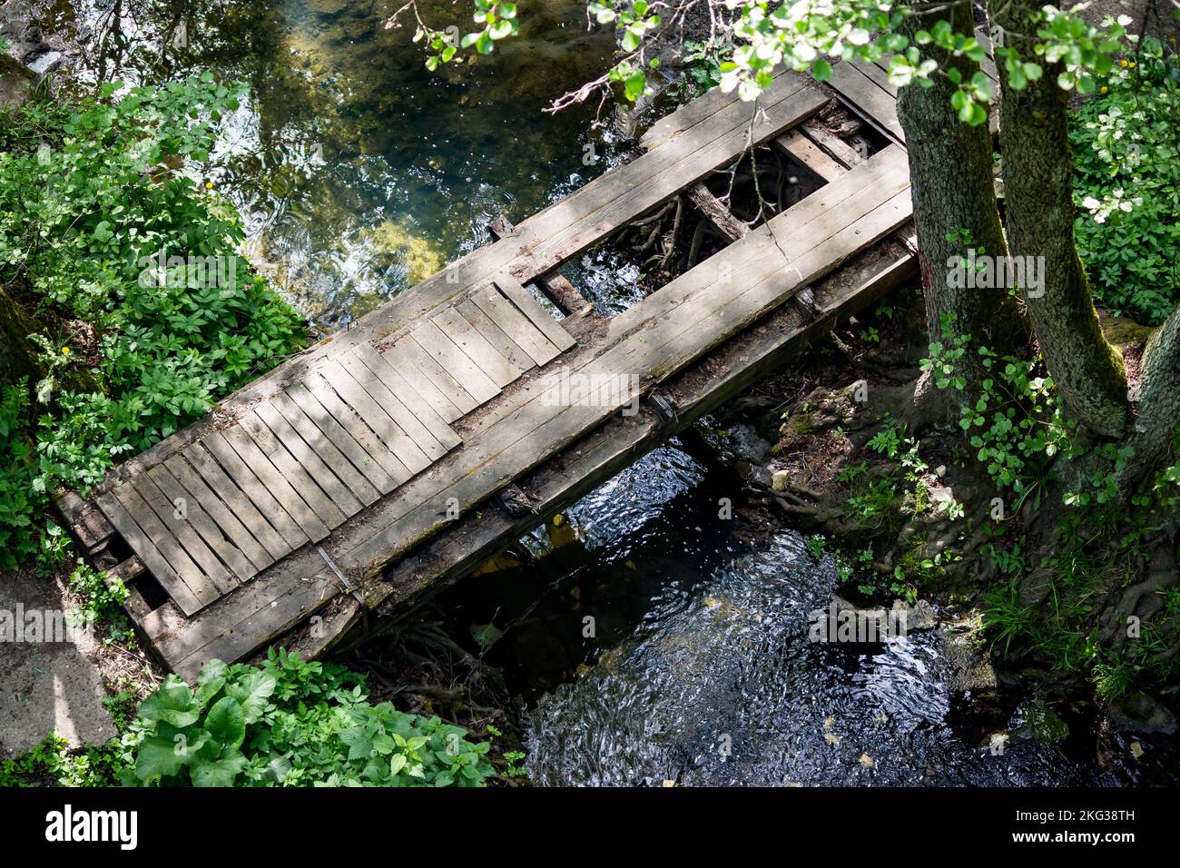 Old footbridge over a running stream with holes in the deck Stock Photo ...