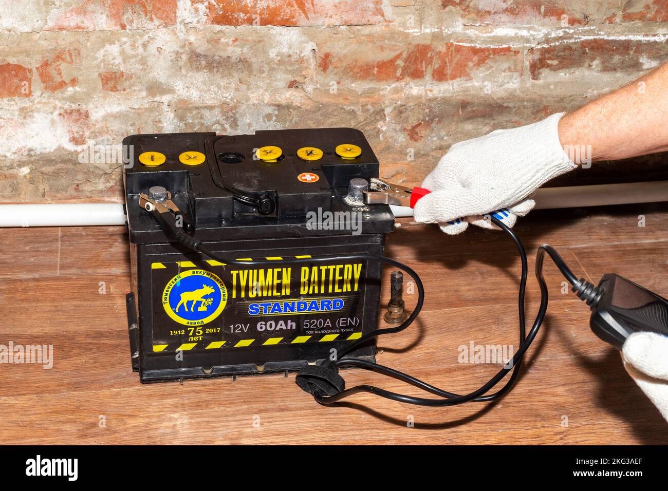 A man measures the capacity and current of a car battery with a ...