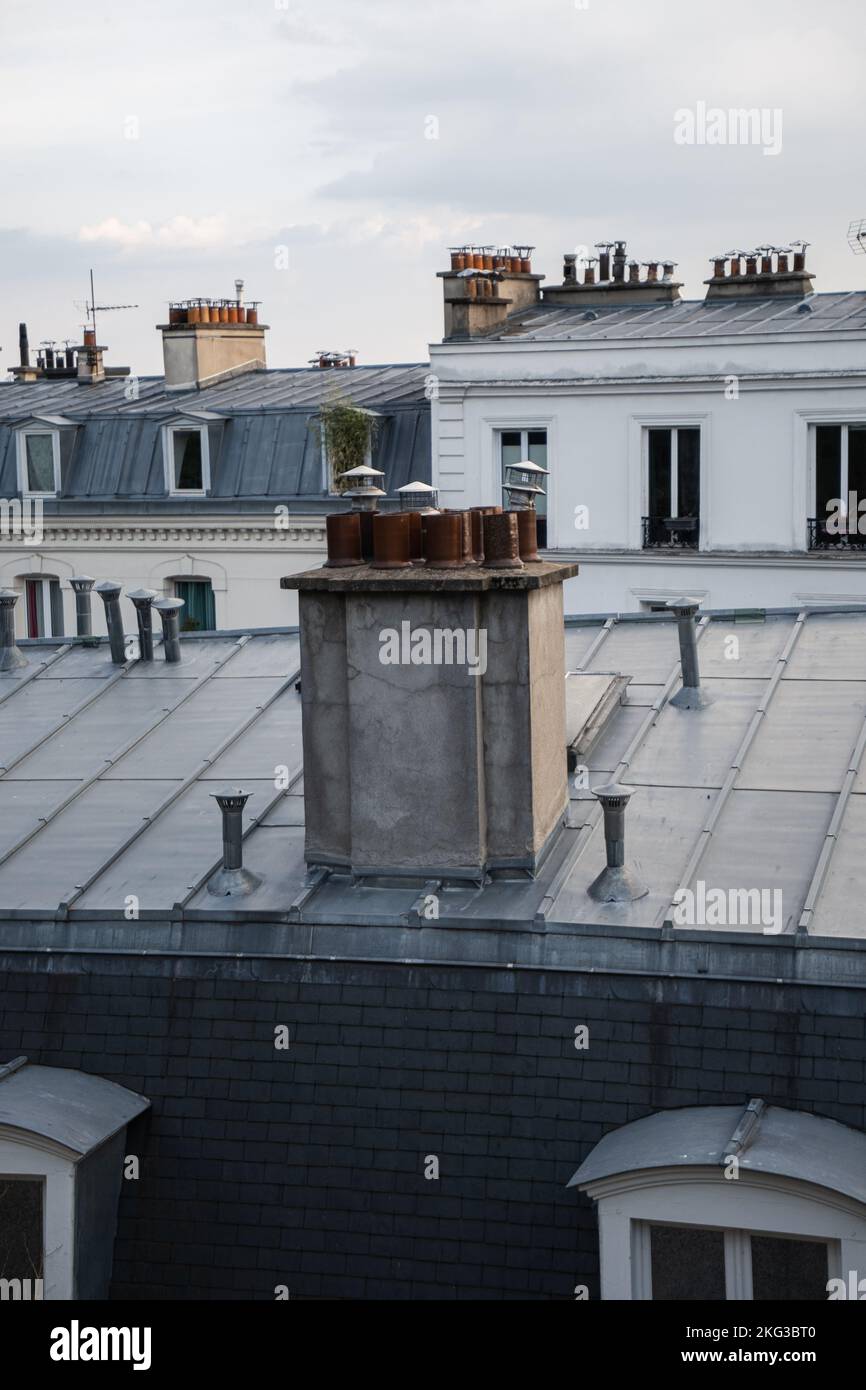 The zinc rooftops with TV antennas and a group of chimneys under cloudy ...