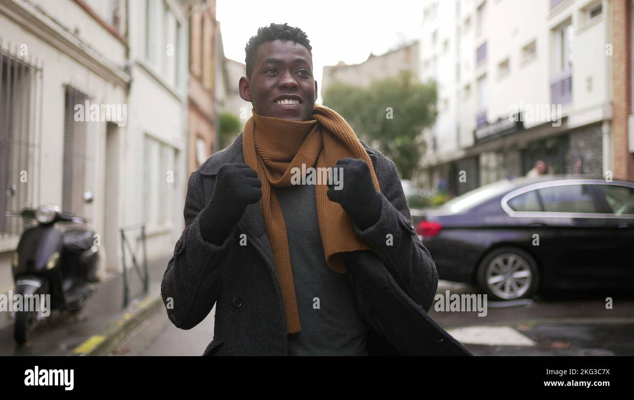 Happy black man celebrating success while walking outside in street ...