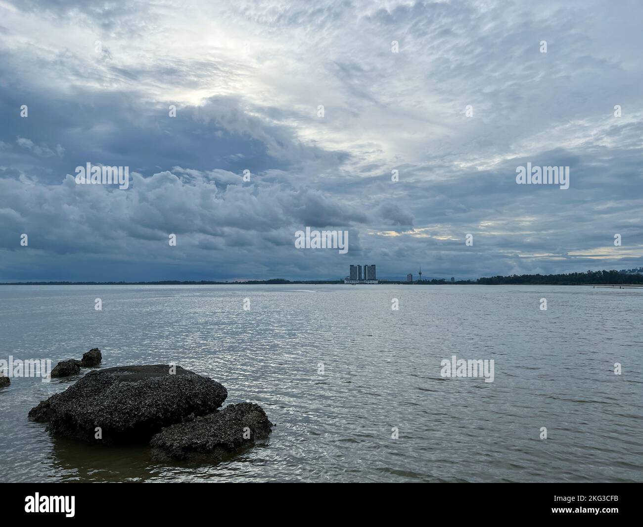 A low-angle of a seascape with rocks in water cloudy gloomy sky ...