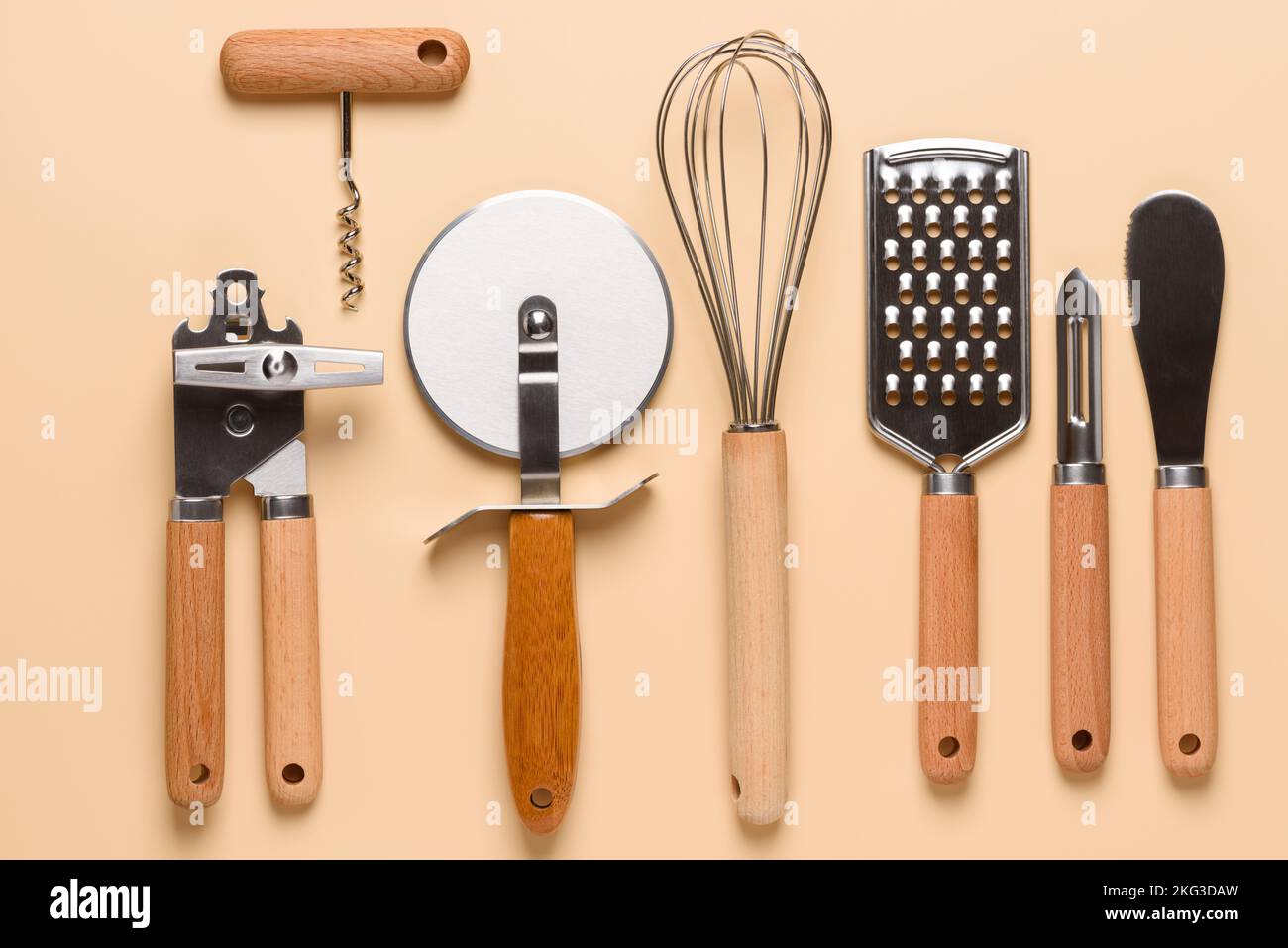 Set of different stainless steel kitchen utensils on beige background ...