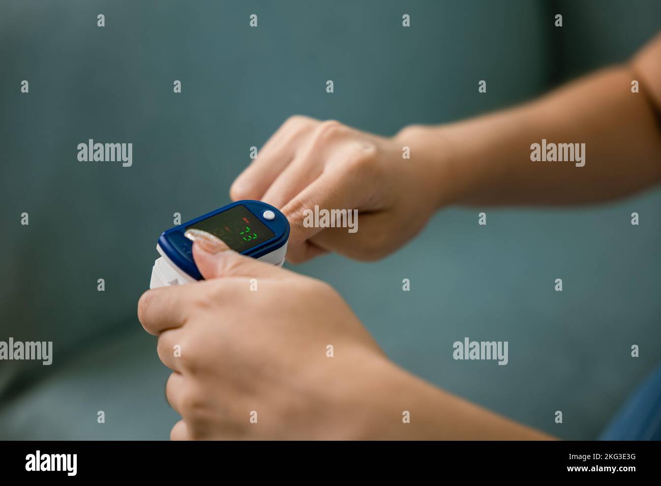 Young woman using pulse oximeter to monitor blood oxygen levels and ...