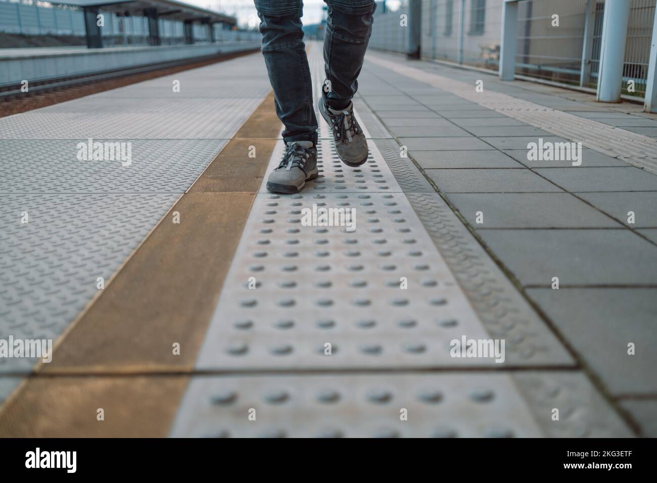 Man jeans and sport sneaker shoes walking at the railway station ...