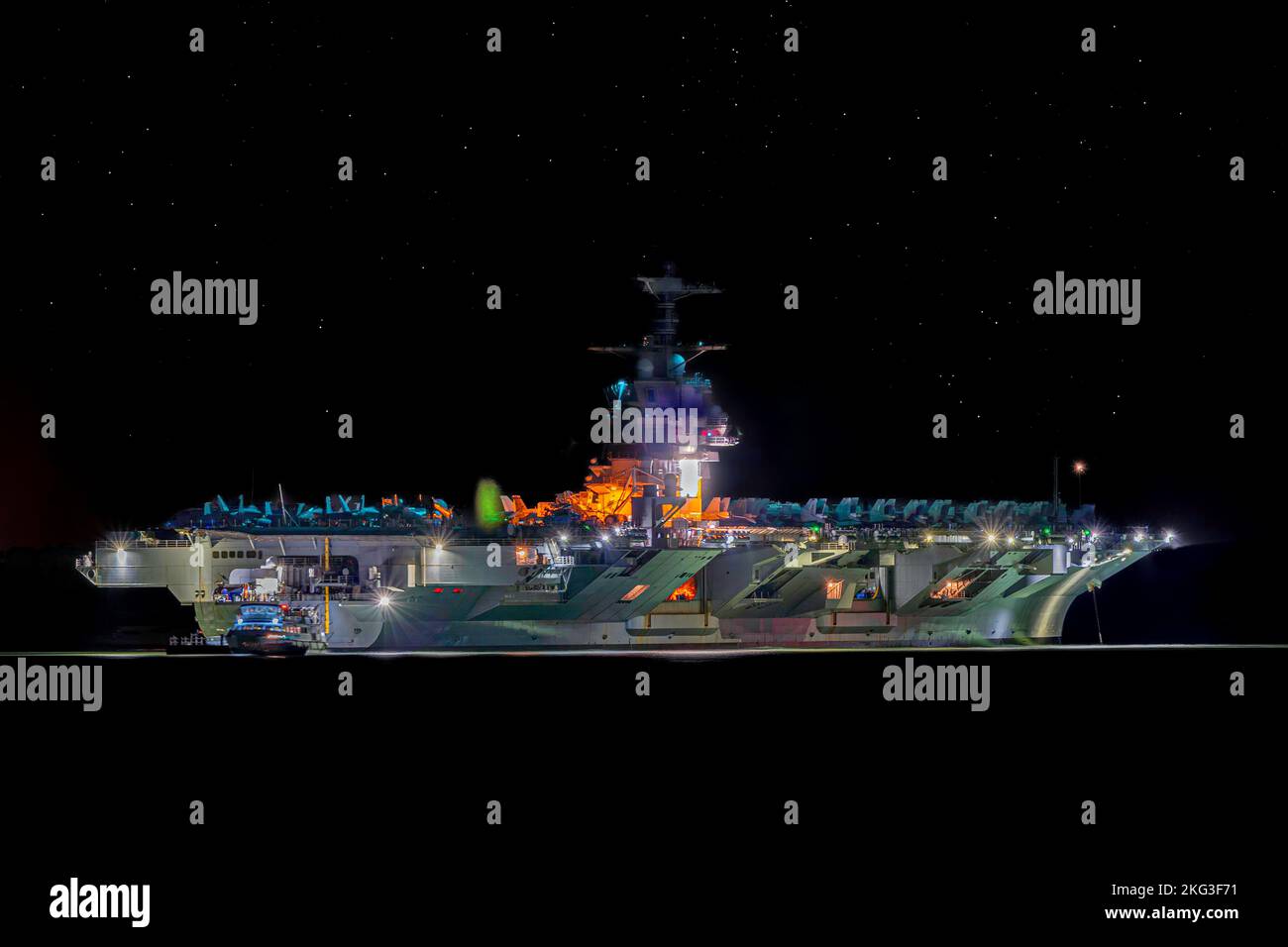 USS Gerald R Ford at anchor at night, beautifully illuminated by her ...