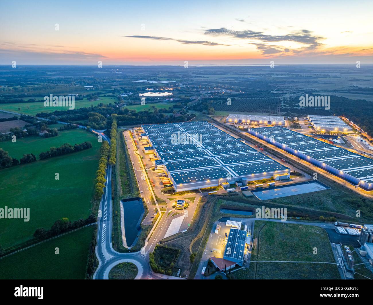 Aerial view of warehouse building at evening near freeway surrounded by ...