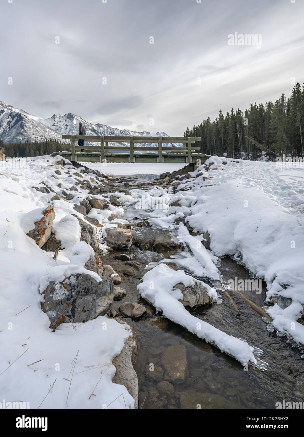 An unrecognizable person crosses a footbridge at Johnson Lake in Banff ...