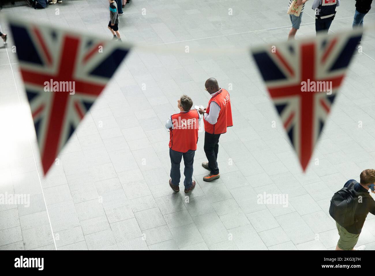Staff members are seen behind a Union flag bunting as passengers walk ...