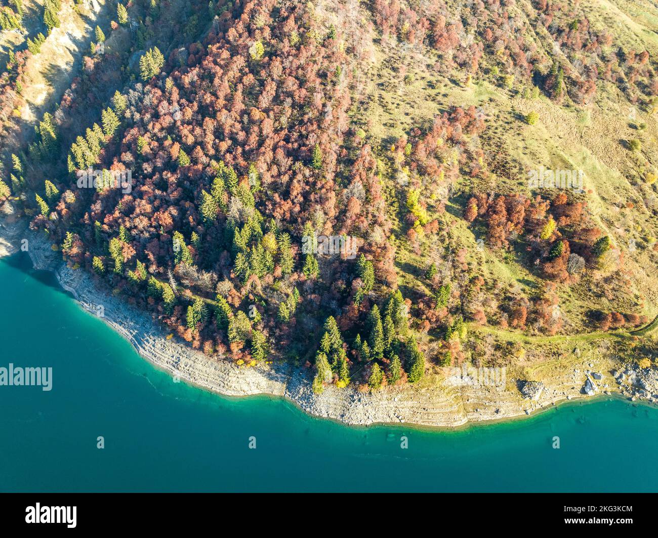 Aerial perspective shot of rural land over a lake with dense forest and ...