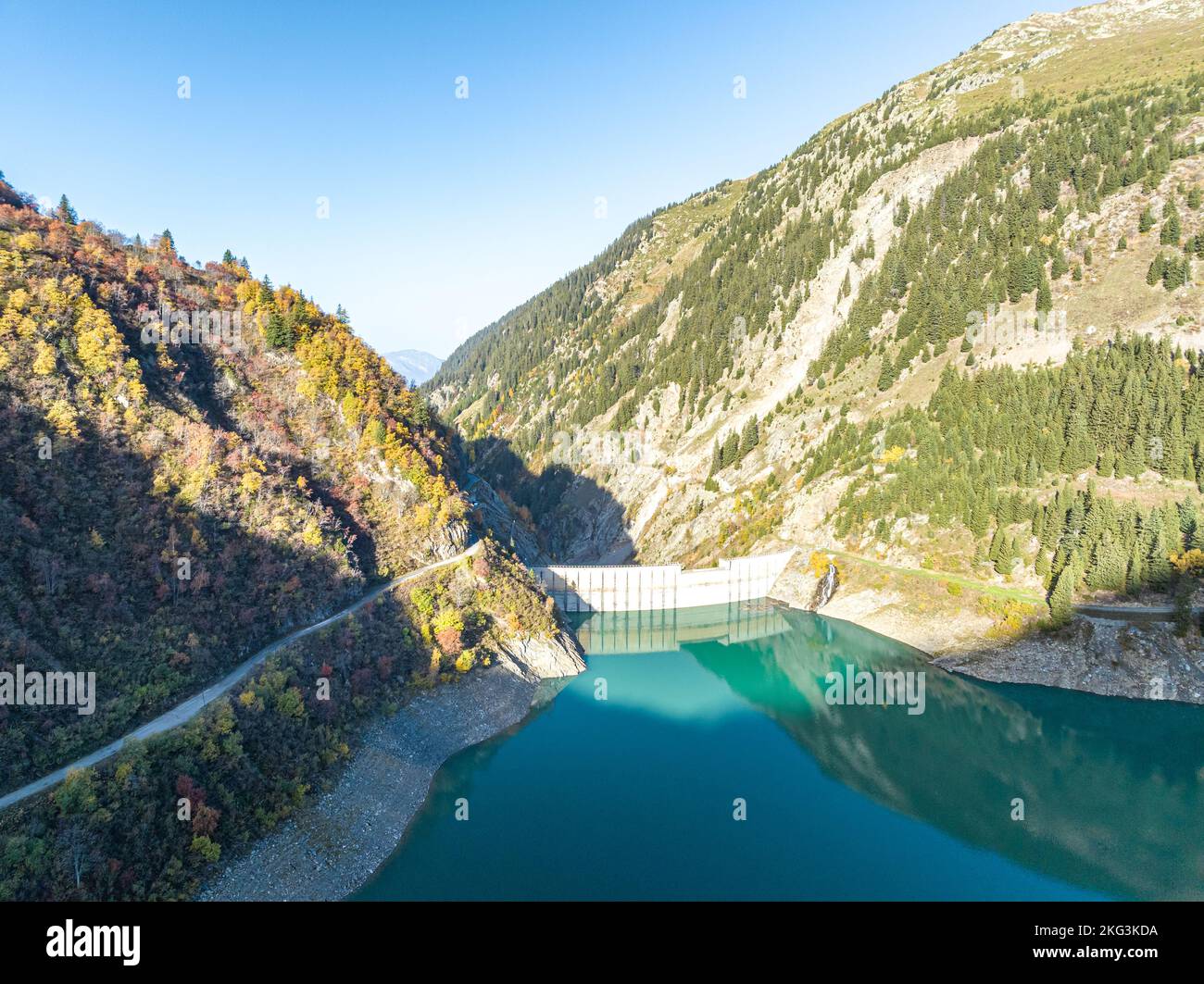 Drone shot of Gittaz lake featuring arch dam walls surrounded by lush ...