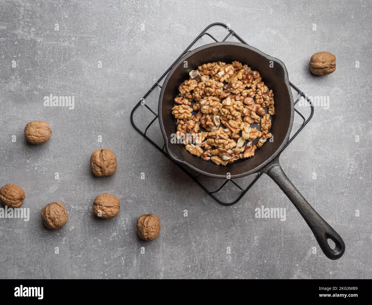 Roasted walnuts in black pan and walnut shells against concrete ...