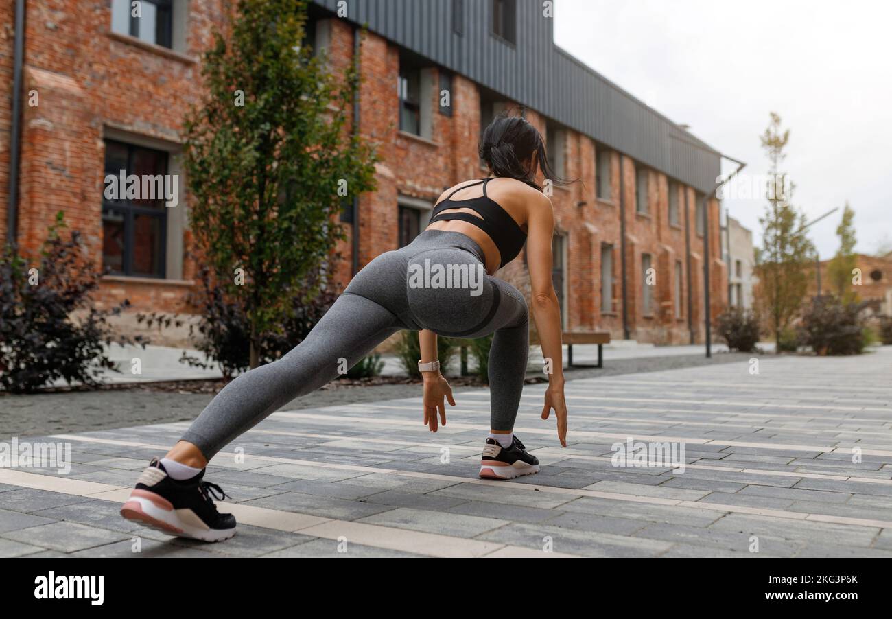 Active woman standing at low start position before urban running Stock ...