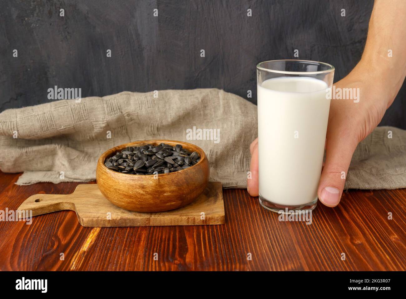 Sunflower milk in a glass, raw seeds, wooden background. Dairy free ...