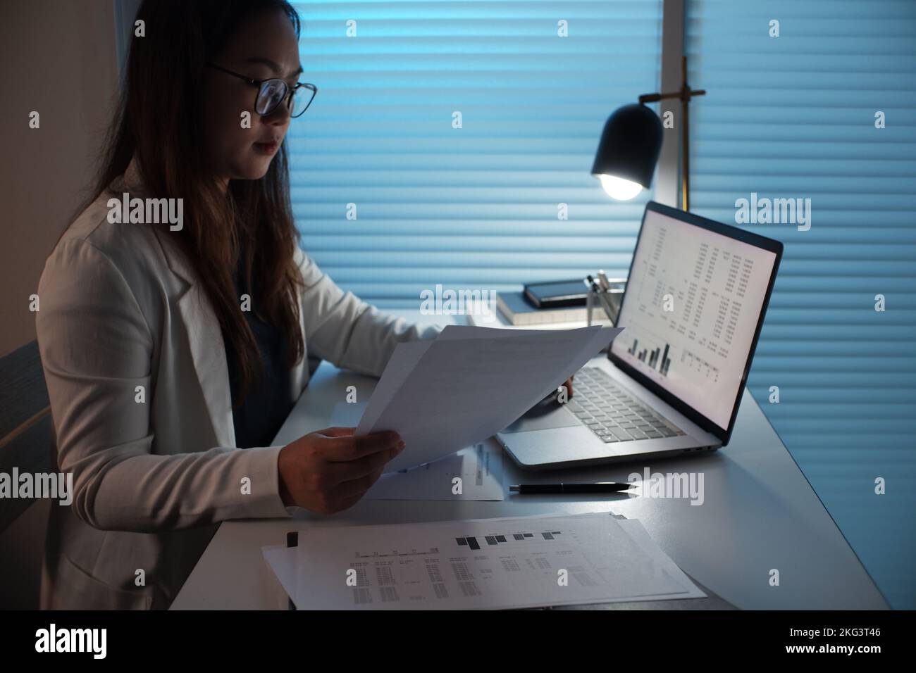 Young Asian women working late at night in dark room, using laptop ...