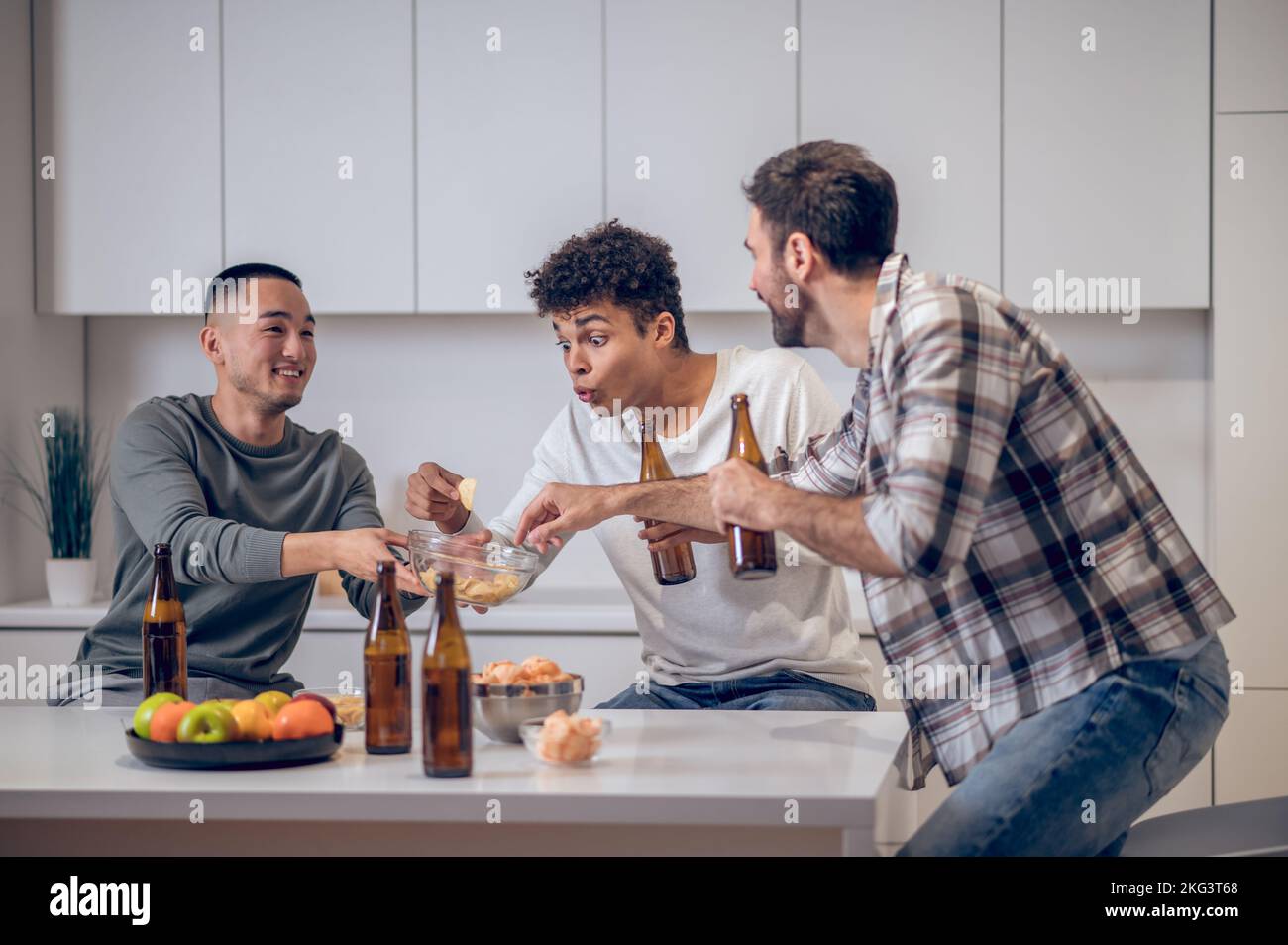 Cheerful guy regaling his two pals with a snack Stock Photo - Alamy