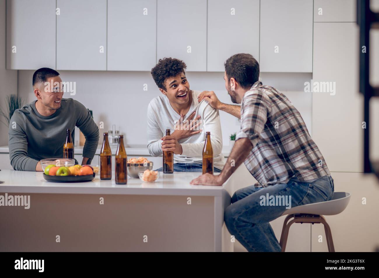 Joyous guy communicating with his pals over beer at home Stock Photo ...