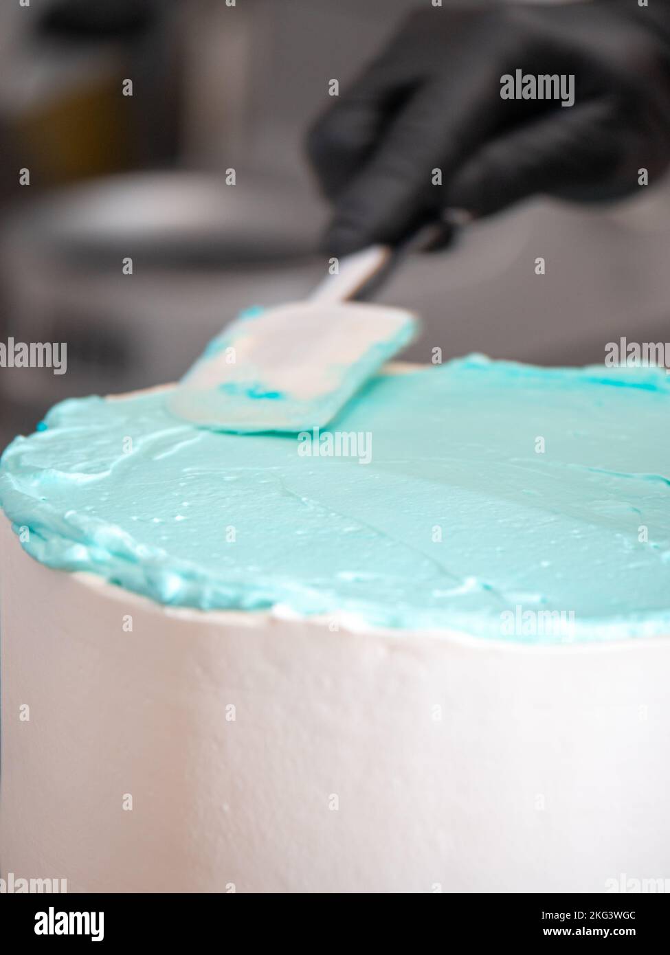 cake designer smoothing a frosted blank cake with turquoise light blue ...