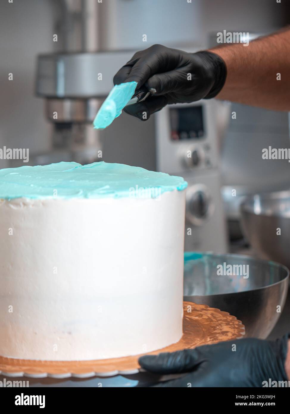 cake designer smoothing a frosted blank cake with turquoise light blue ...