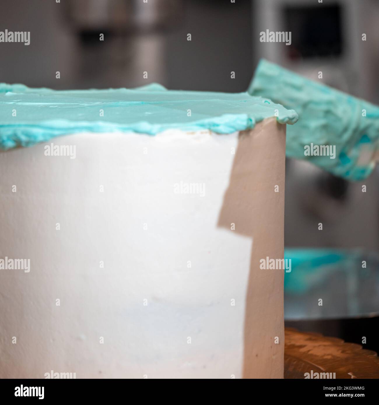 cake designer smoothing a frosted blank cake with turquoise light blue ...