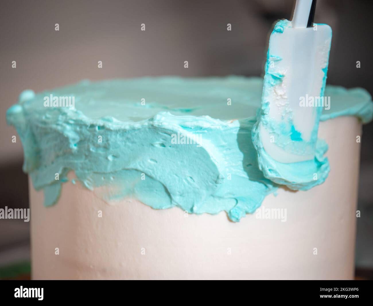 cake designer smoothing a frosted blank cake with turquoise light blue ...