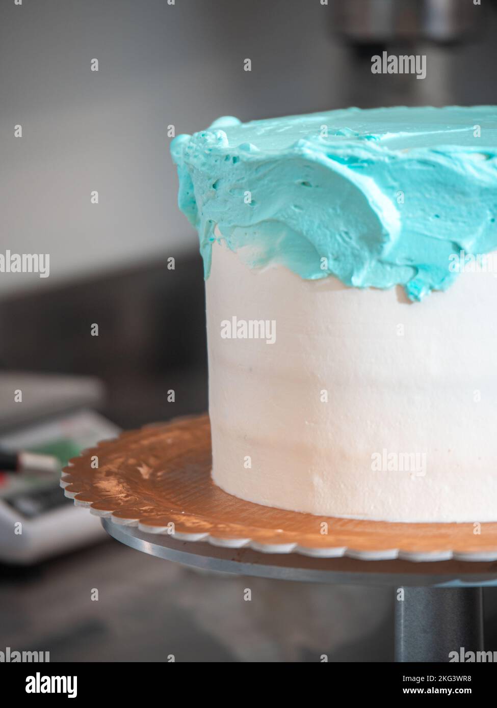 cake designer smoothing a frosted blank cake with turquoise light blue ...