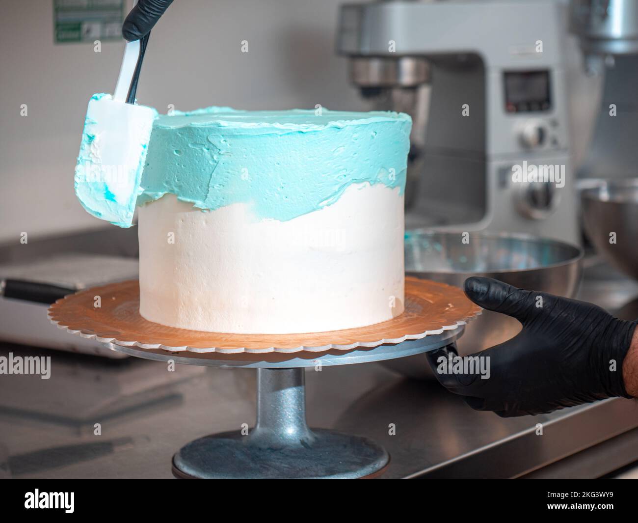 cake designer smoothing a frosted blank cake with turquoise light blue ...