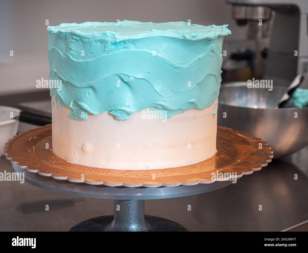 cake designer smoothing a frosted blank cake with turquoise light blue ...