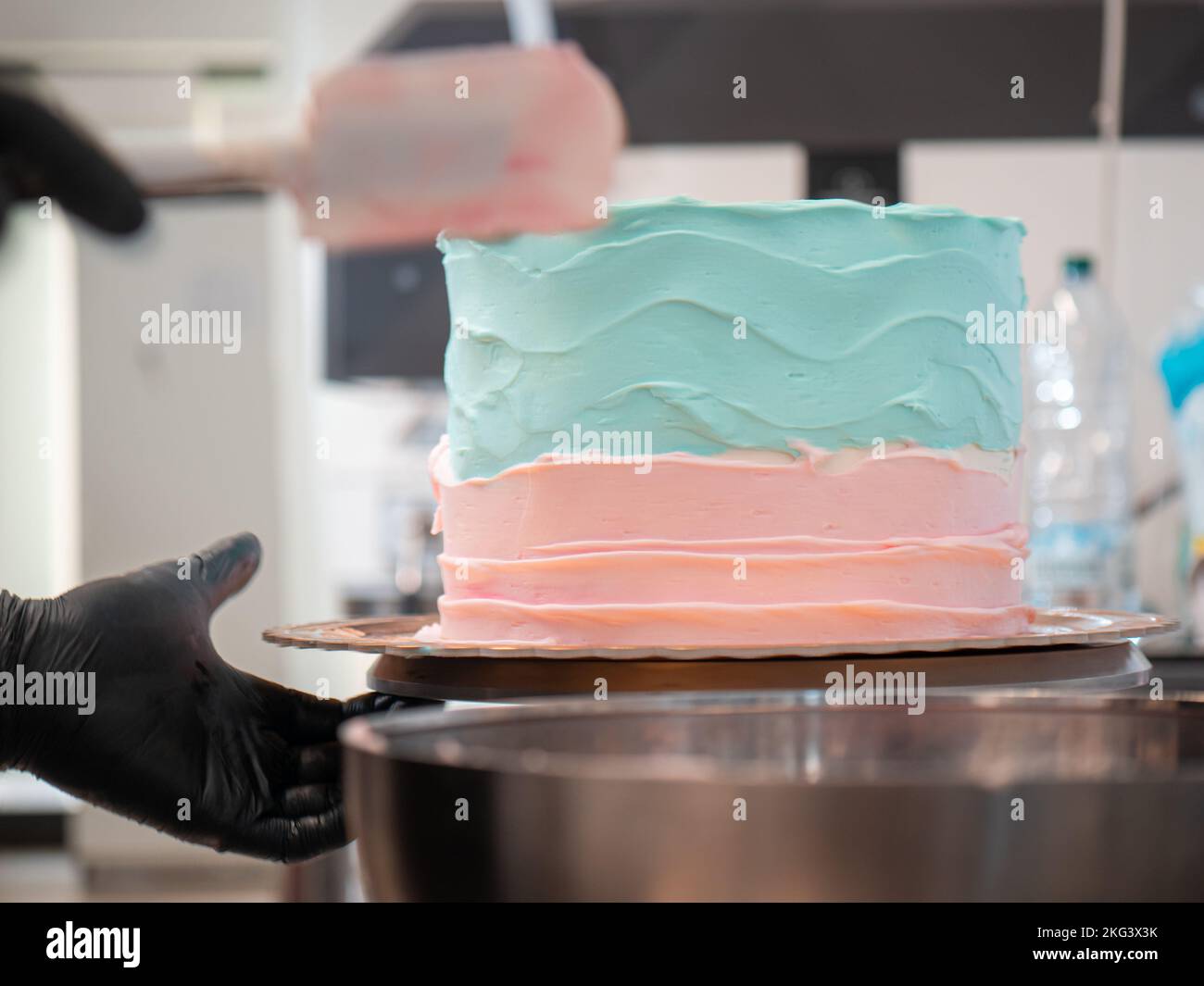 cake designer smoothing a frosted blank cake with turquoise light blue ...