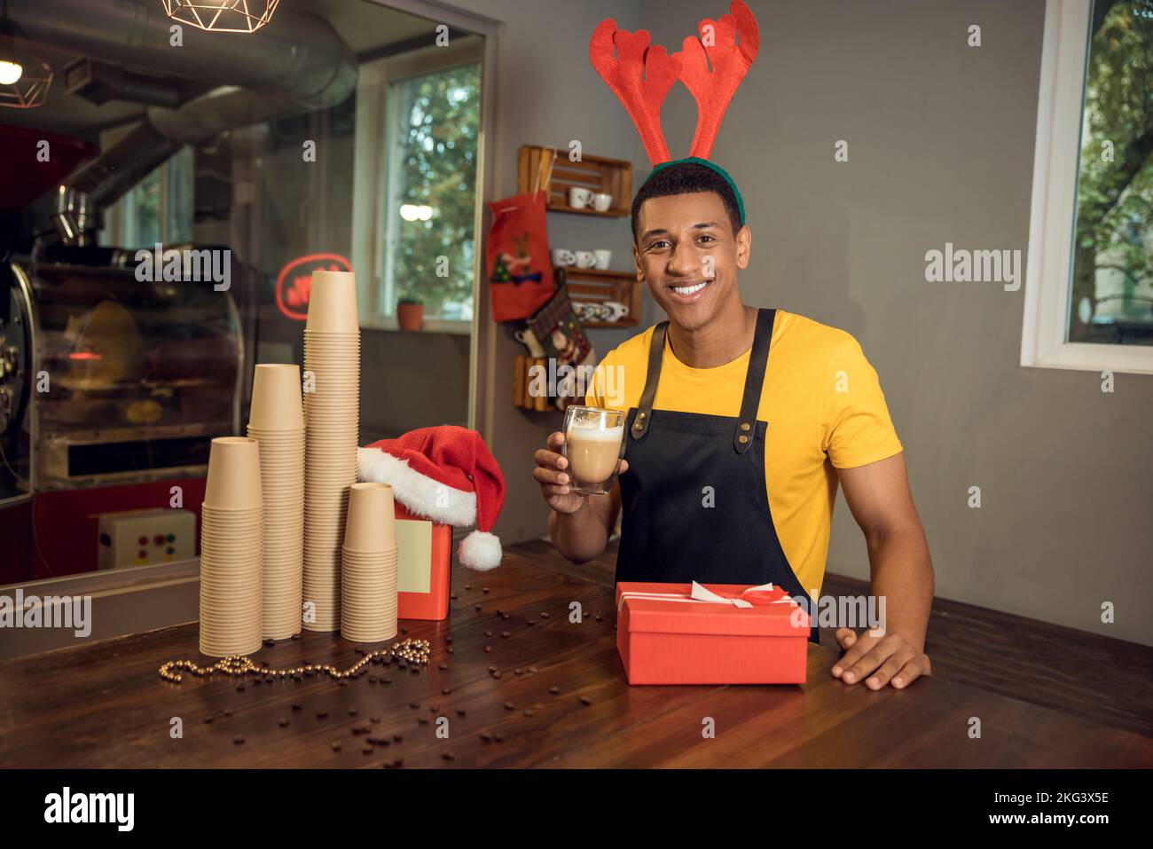Pleased barista with a coffee beverage standing at the table Stock ...