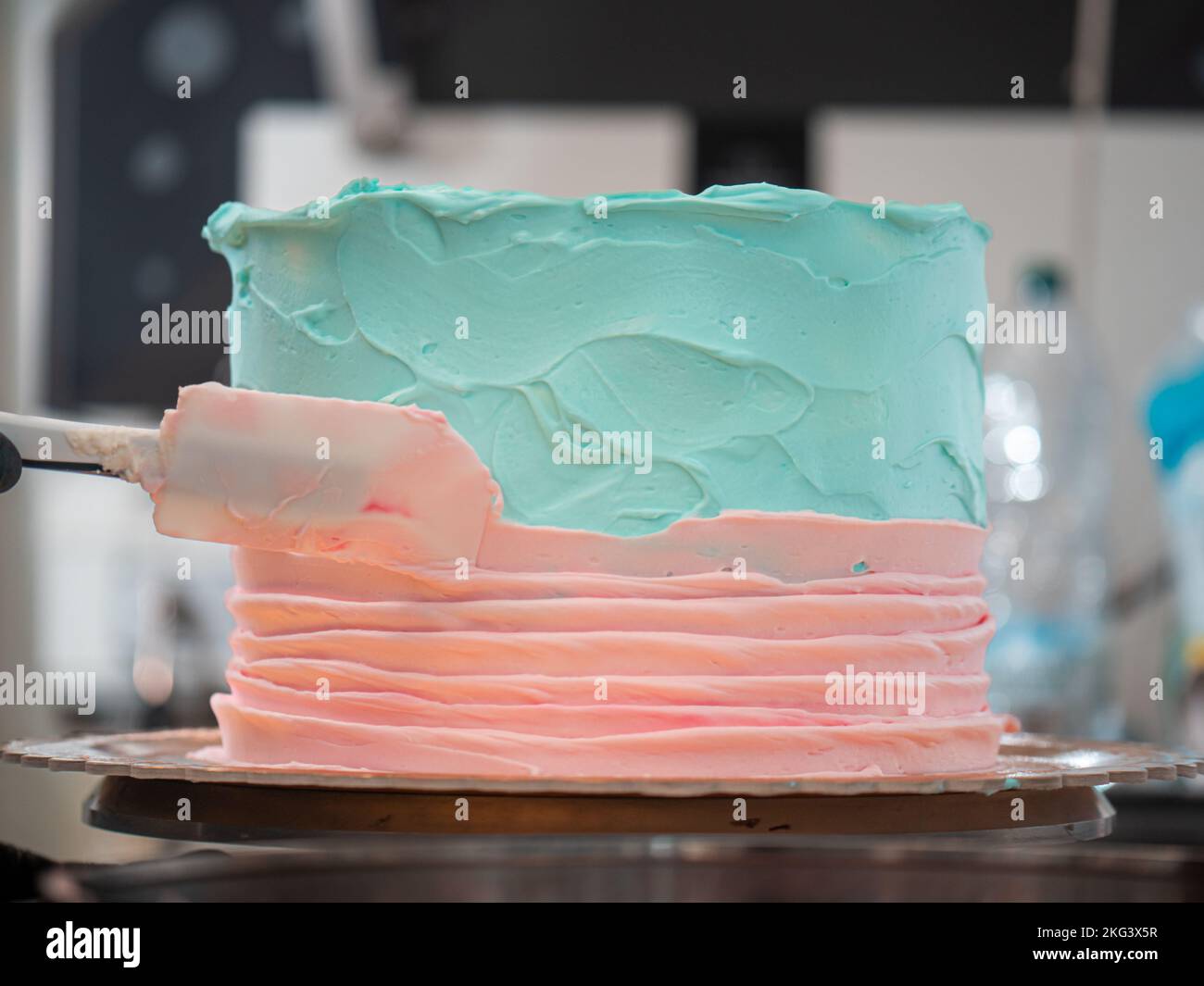 cake designer smoothing a frosted blank cake with turquoise light blue ...