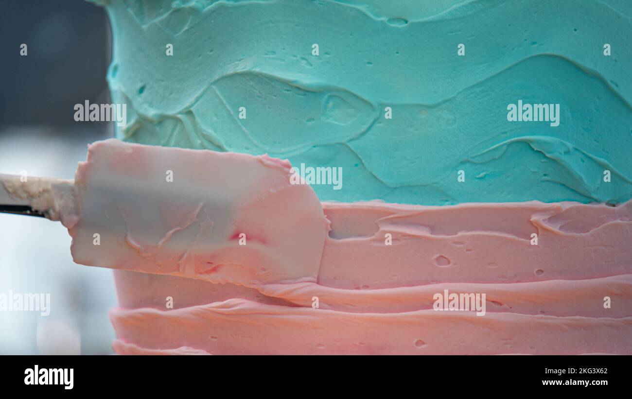 cake designer smoothing a frosted blank cake with turquoise light blue ...