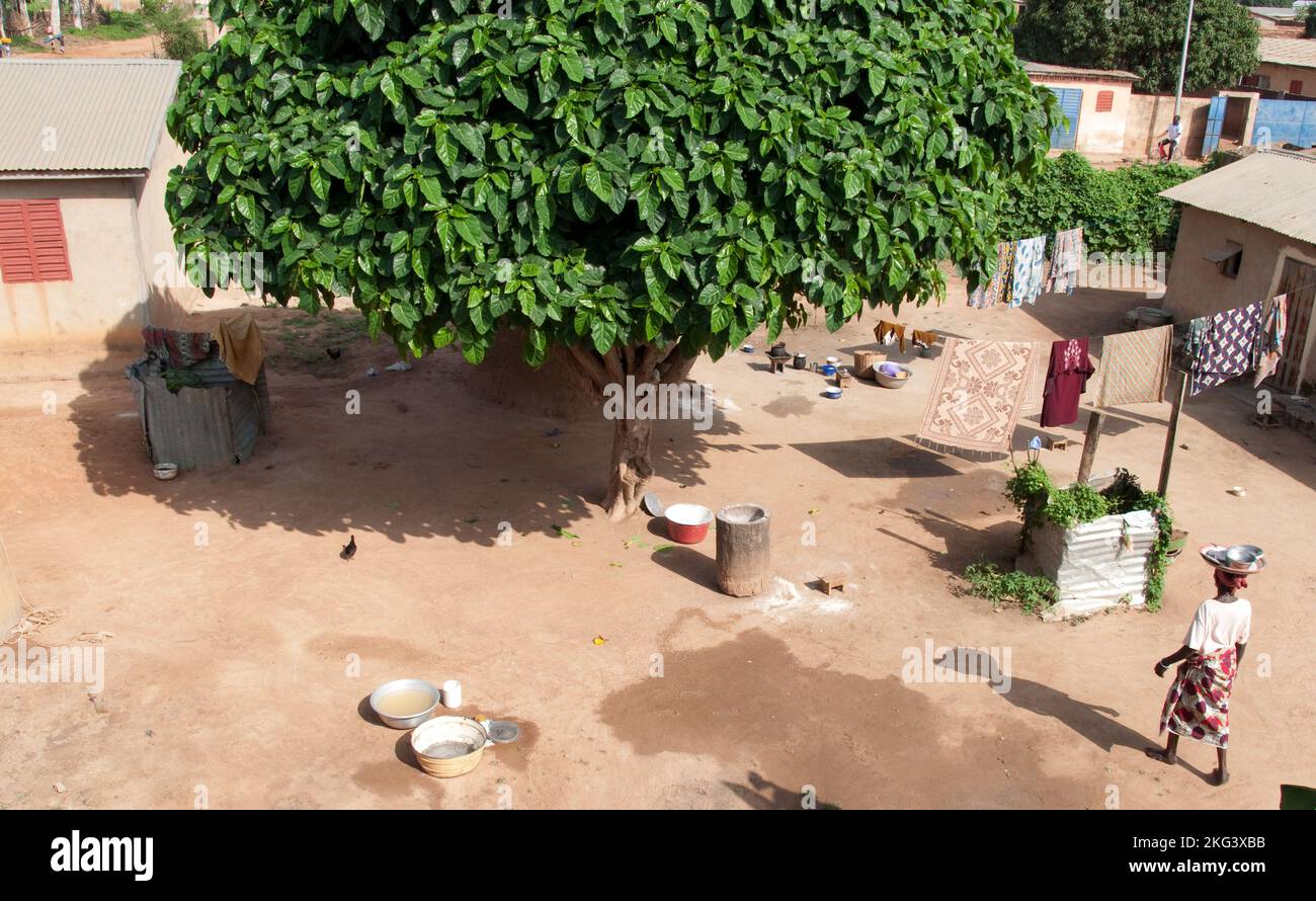 Elderly woman walking across courtyard with cooking utensils on her ...