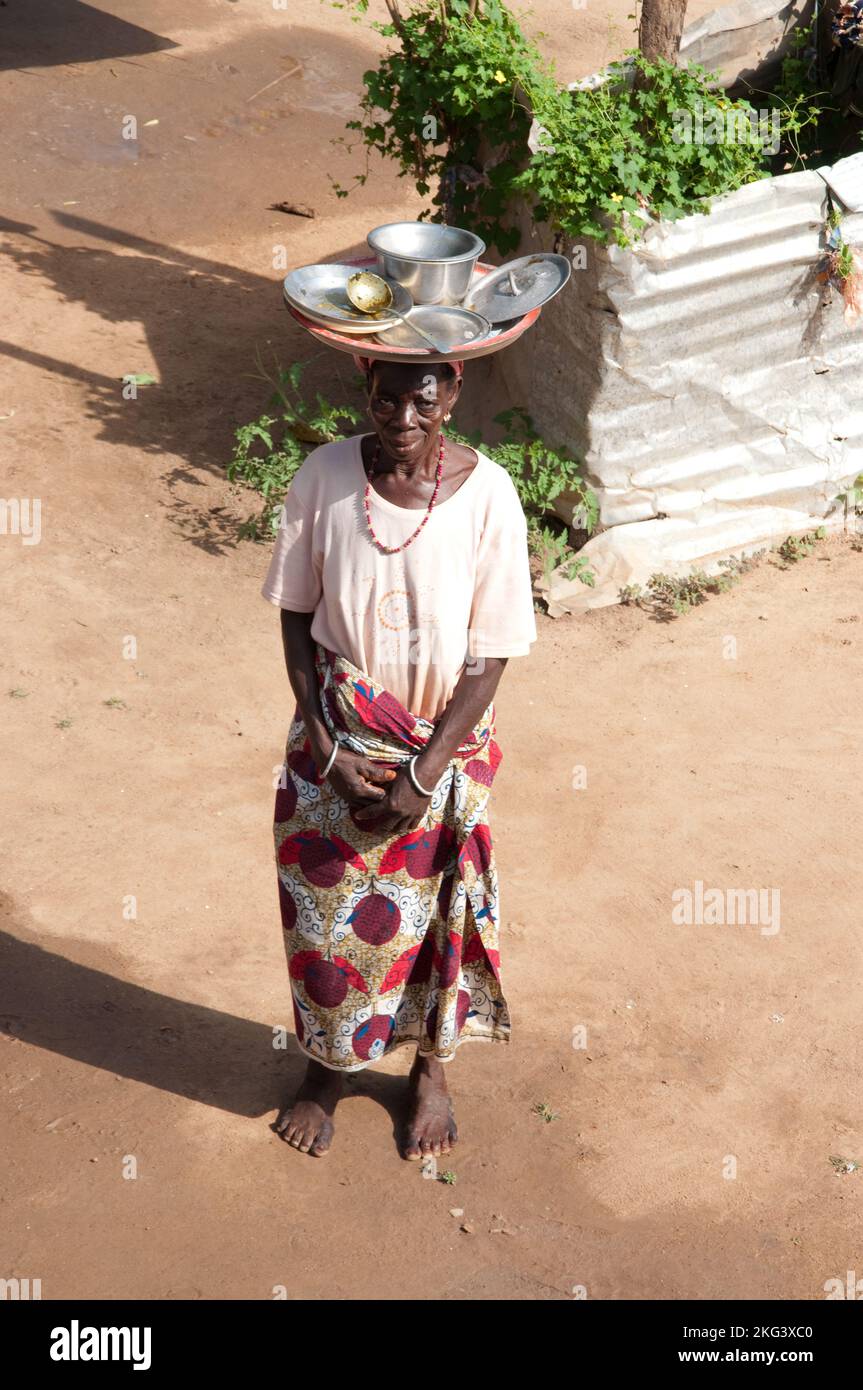 Elderly woman carrying cooking utensils on her head, Pehunco, Atacora ...