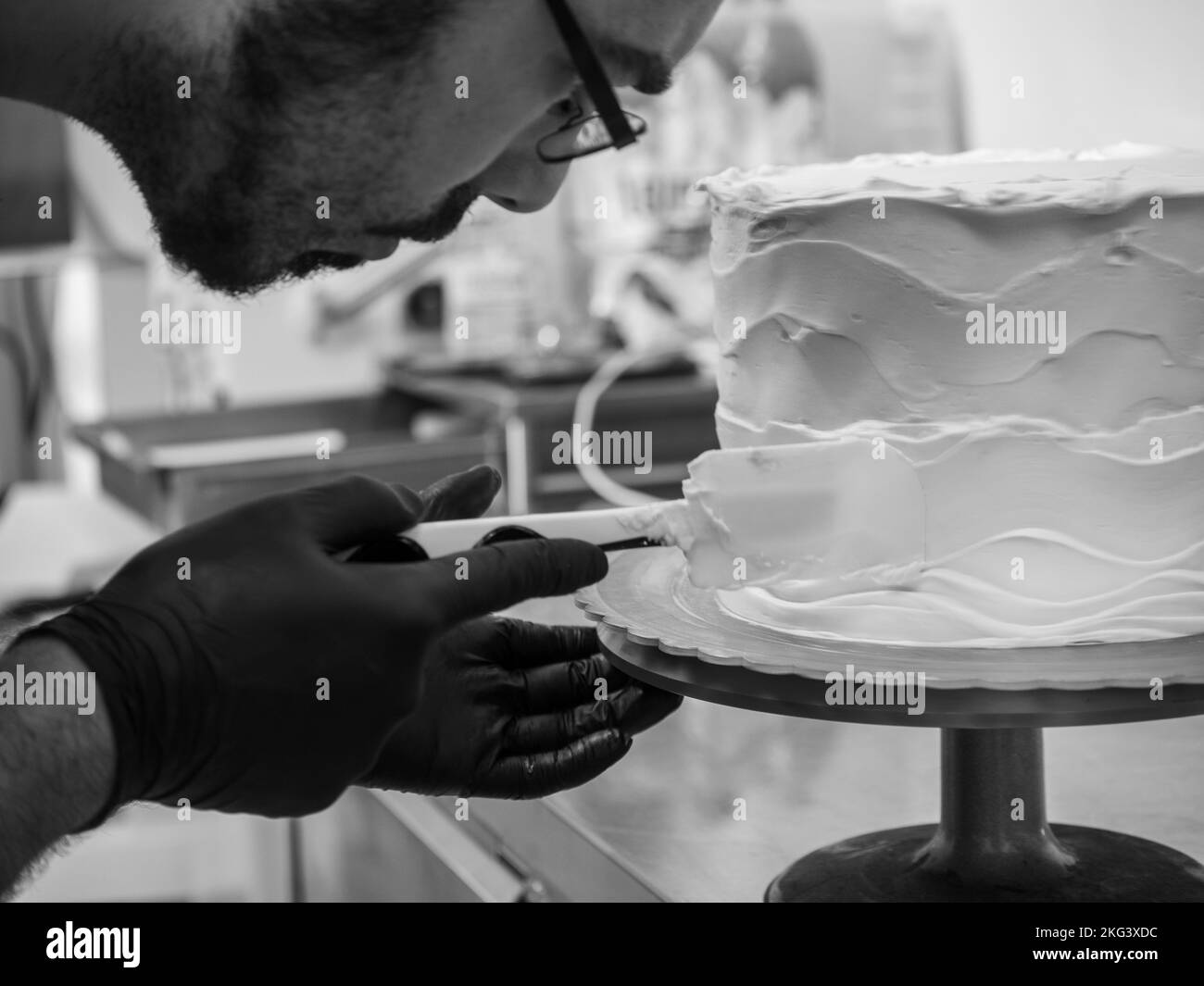 cake designer smoothing a frosted blank cake with turquoise light blue ...