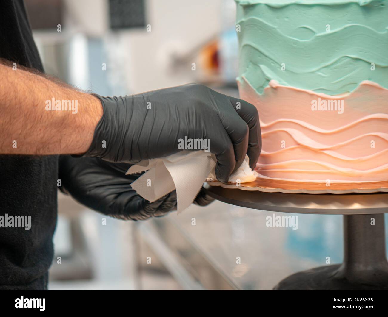 cake designer smoothing a frosted blank cake with turquoise light blue ...