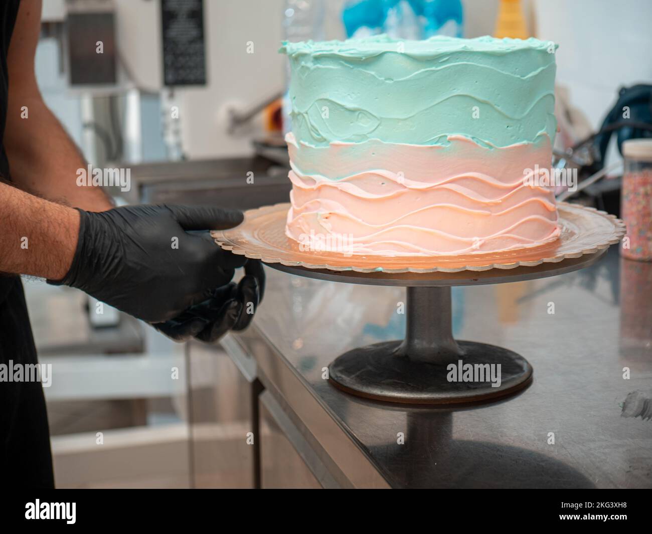 cake designer smoothing a frosted blank cake with turquoise light blue ...