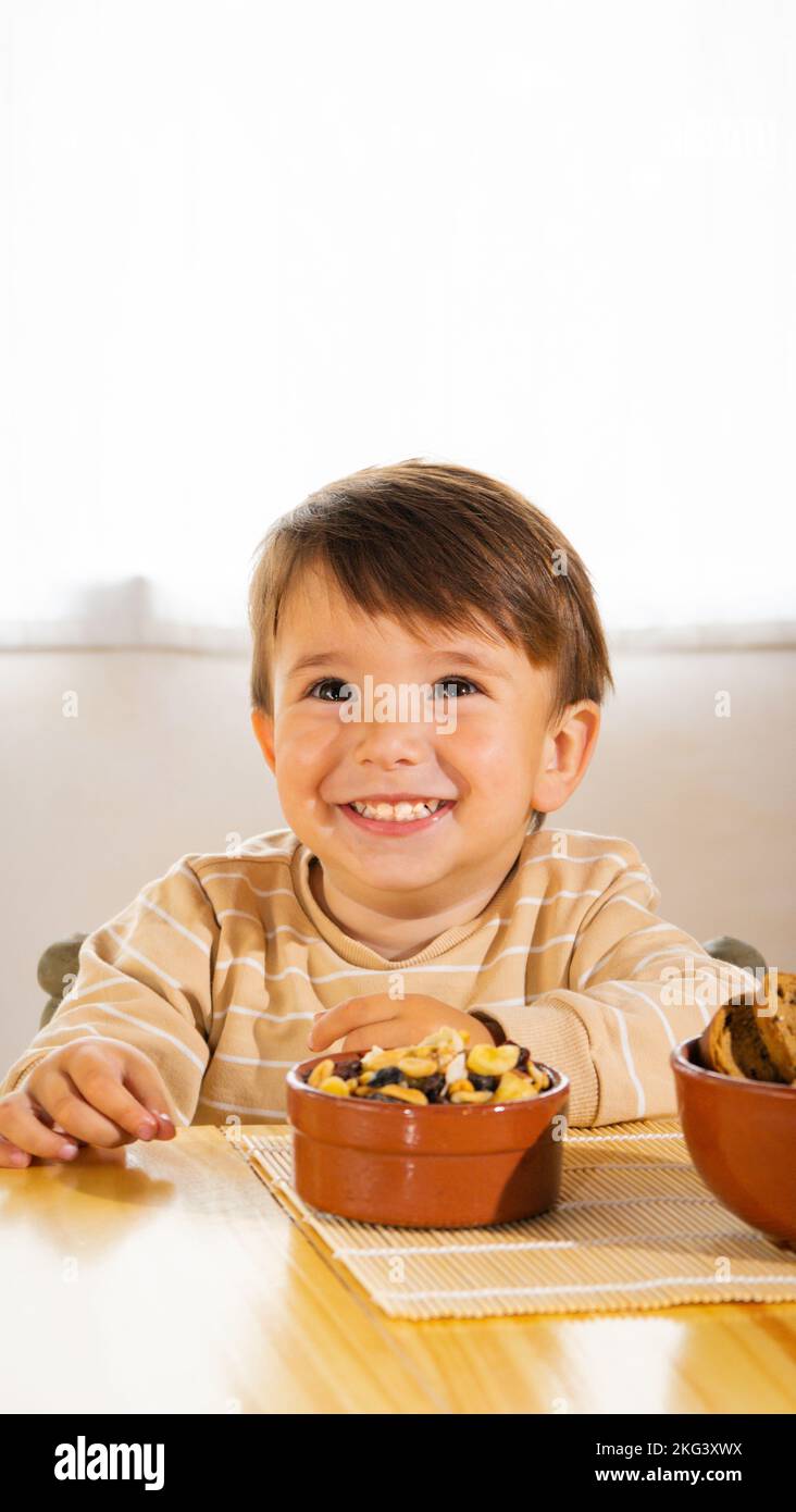 a young mother serves her son a healthy breakfast and sits next to the ...