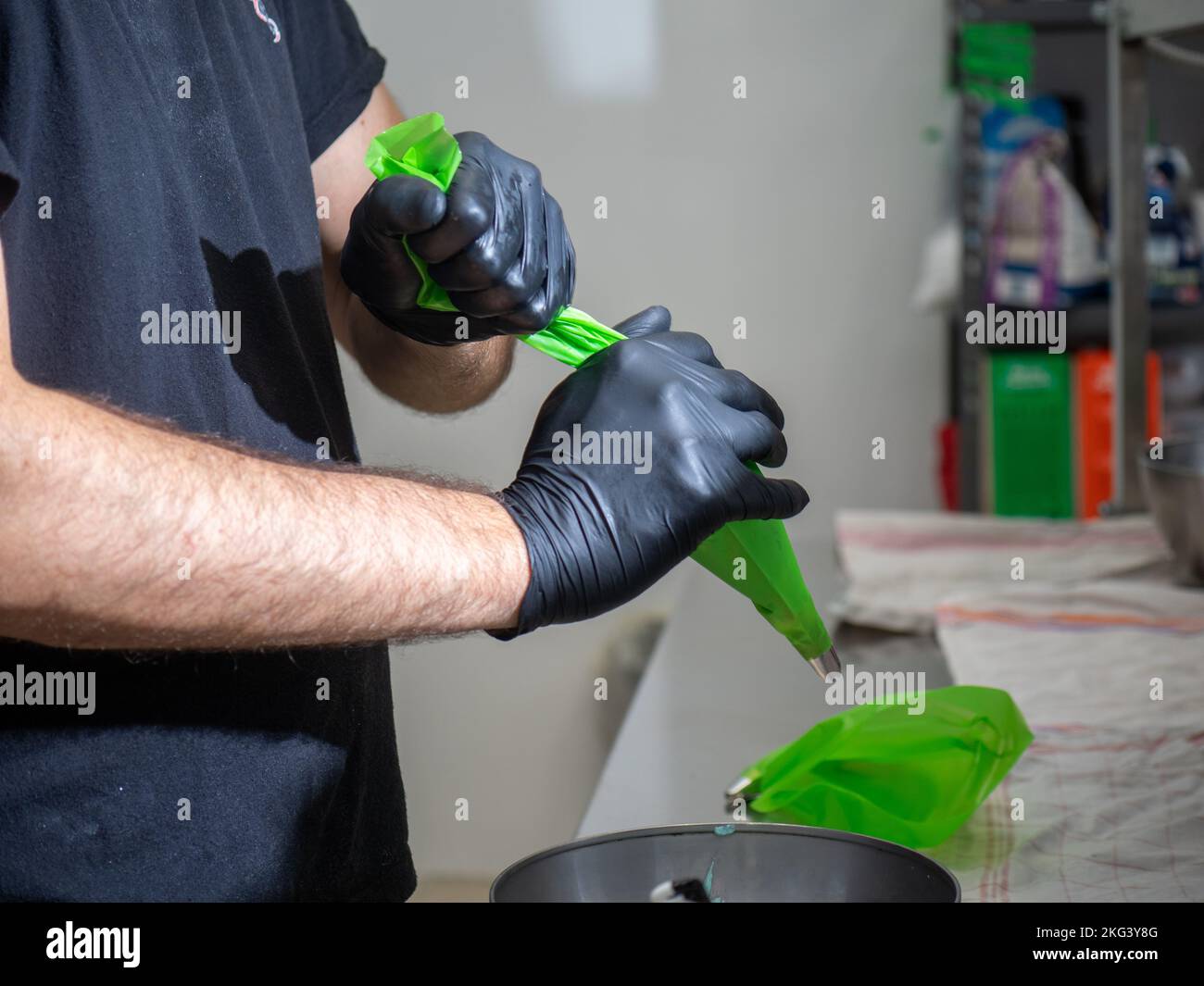 chef using using piping bag pink butter cream filling to decorate ...