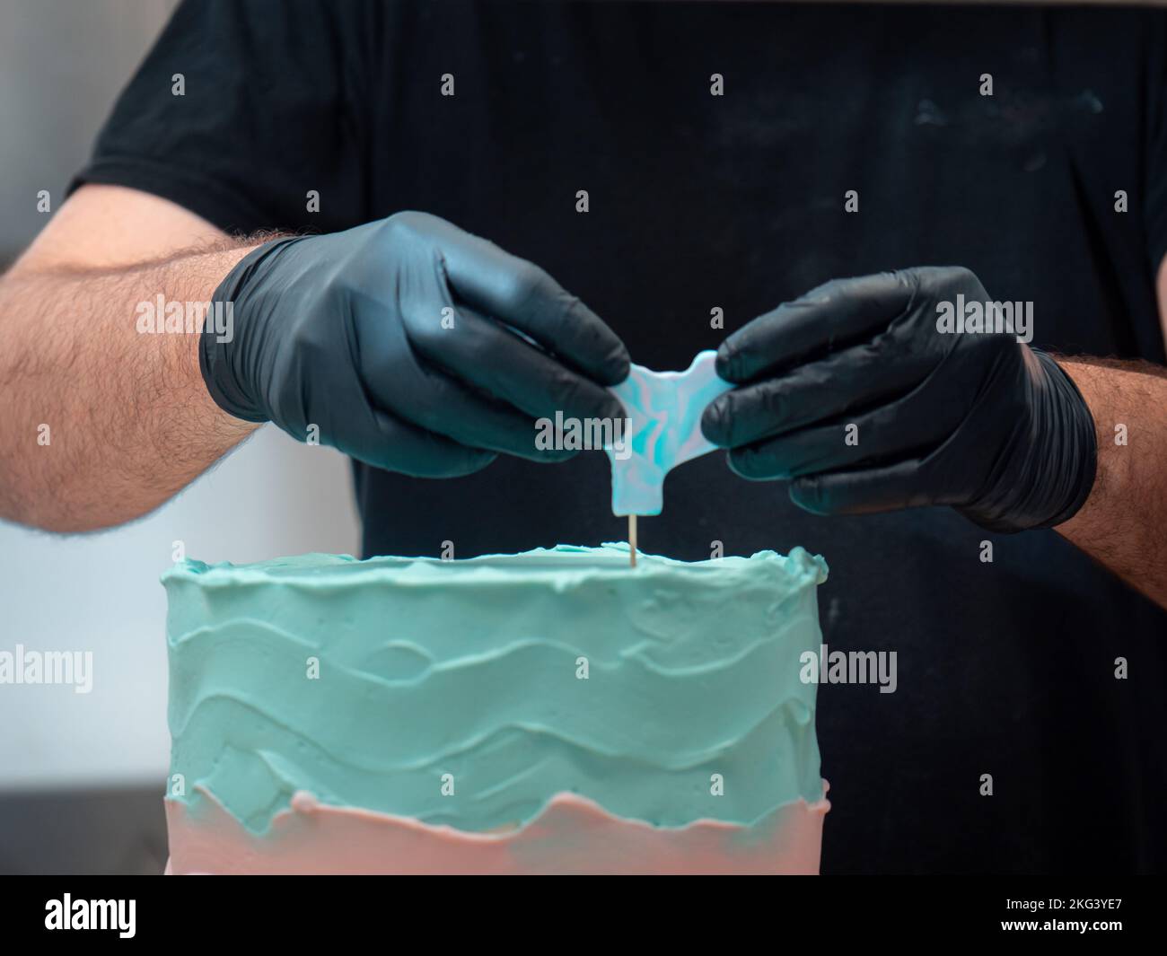 cake designer smoothing a frosted blank cake with turquoise light blue ...