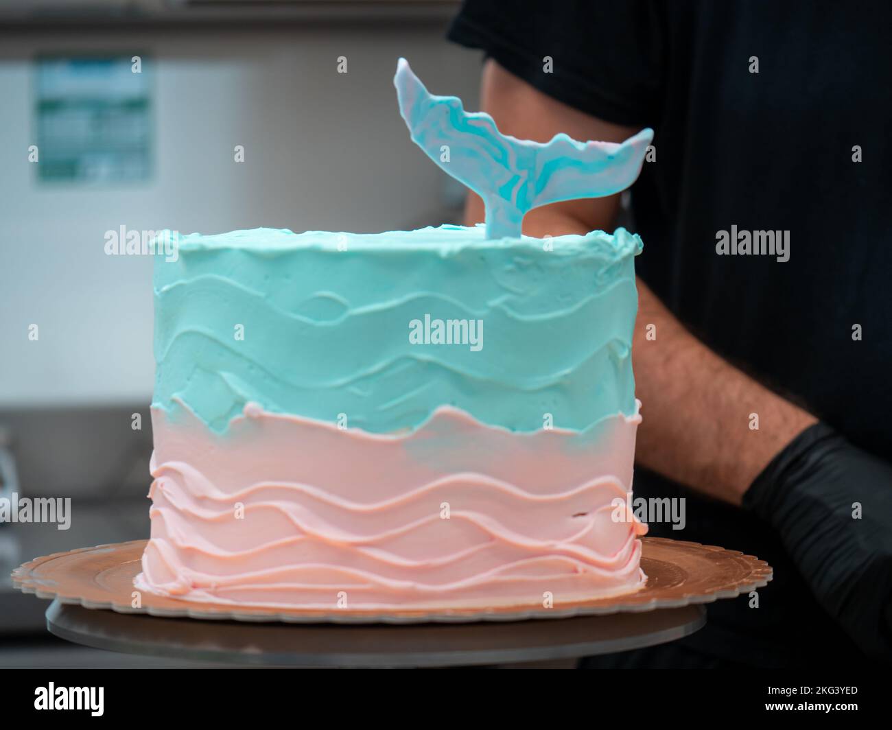cake designer smoothing a frosted blank cake with turquoise light blue ...