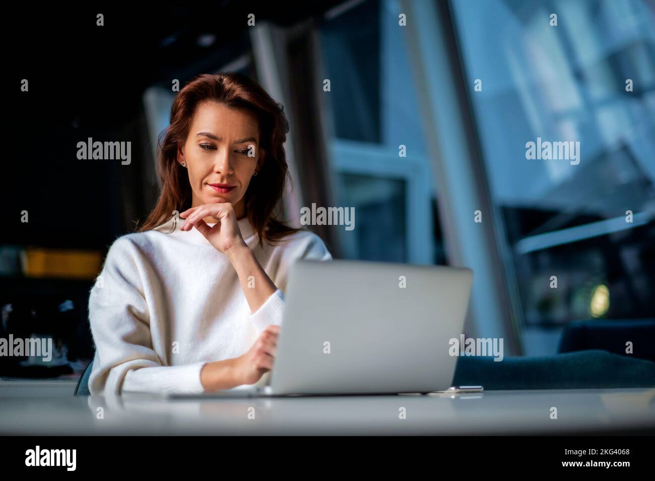 Middle aged business woman using laptop while sitting at desk at the ...