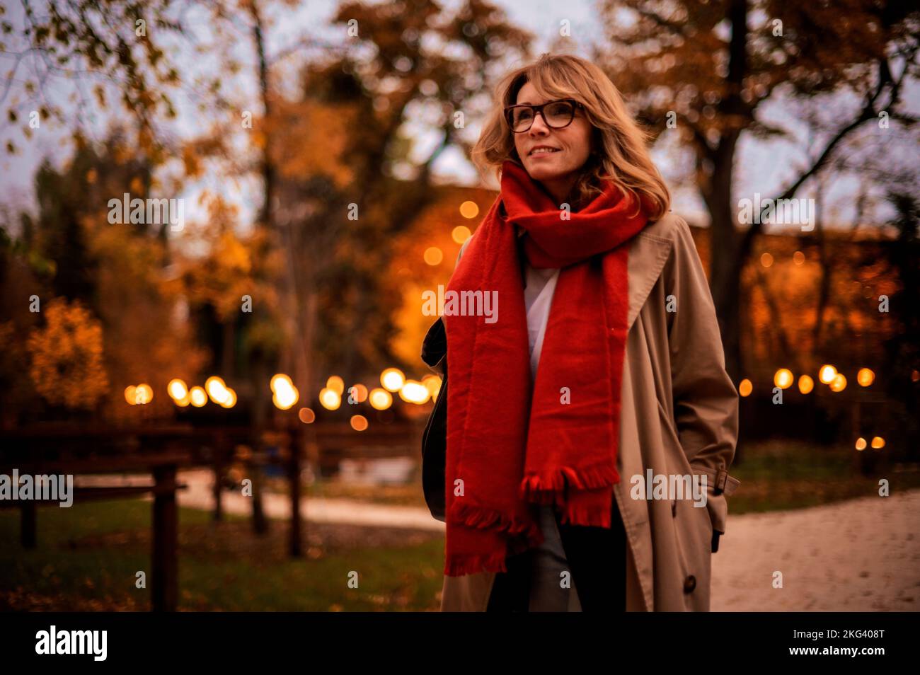 Fashionable middle aged woman walking in the street and enjoying autumn ...