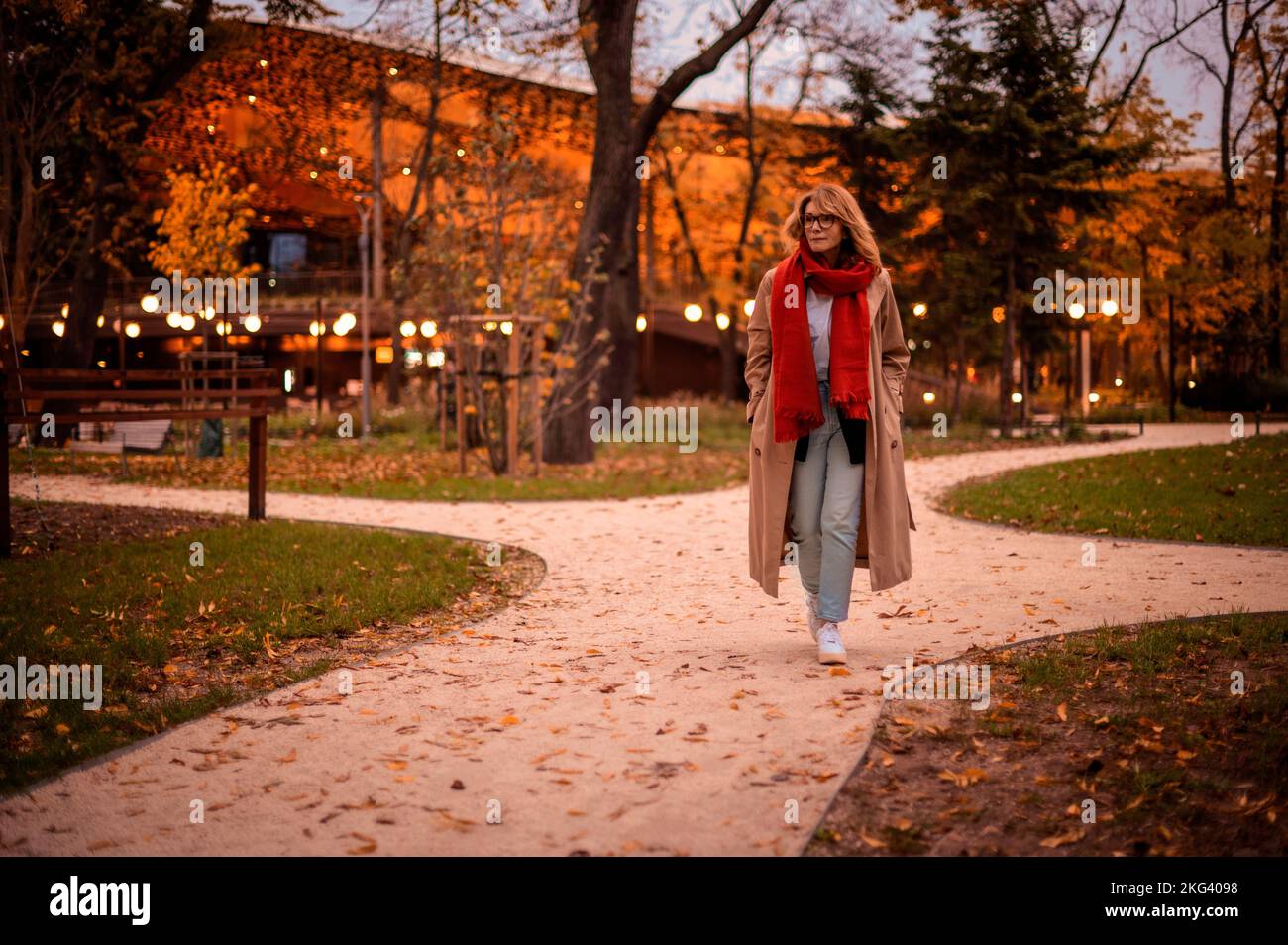 Fashionable middle aged woman walking in the street and enjoying autumn ...