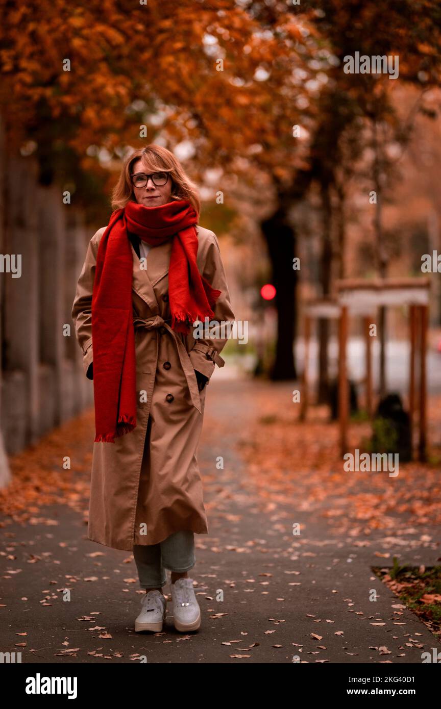 Fashionable middle aged woman walking in the street and enjoying autumn ...